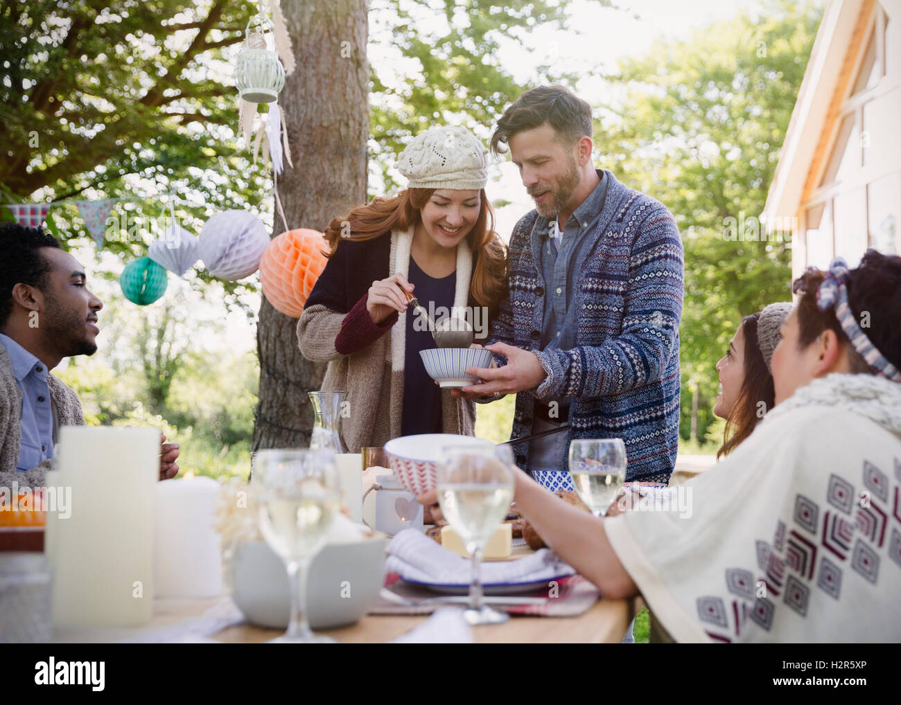 Couple serving lunch to friends at patio table Stock Photo - Alamy