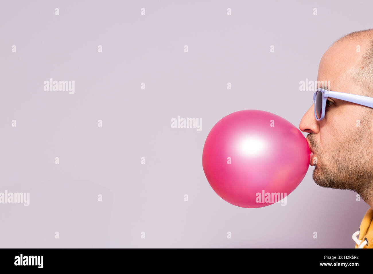 Man blowing pink chewing gum on a light purple background Stock Photo ...