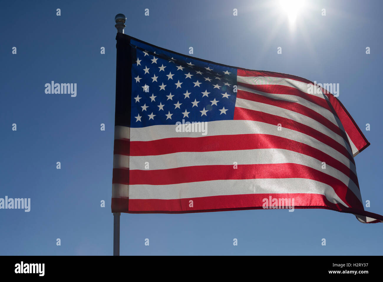 American flag flying on a clear day with sun flare Stock Photo - Alamy