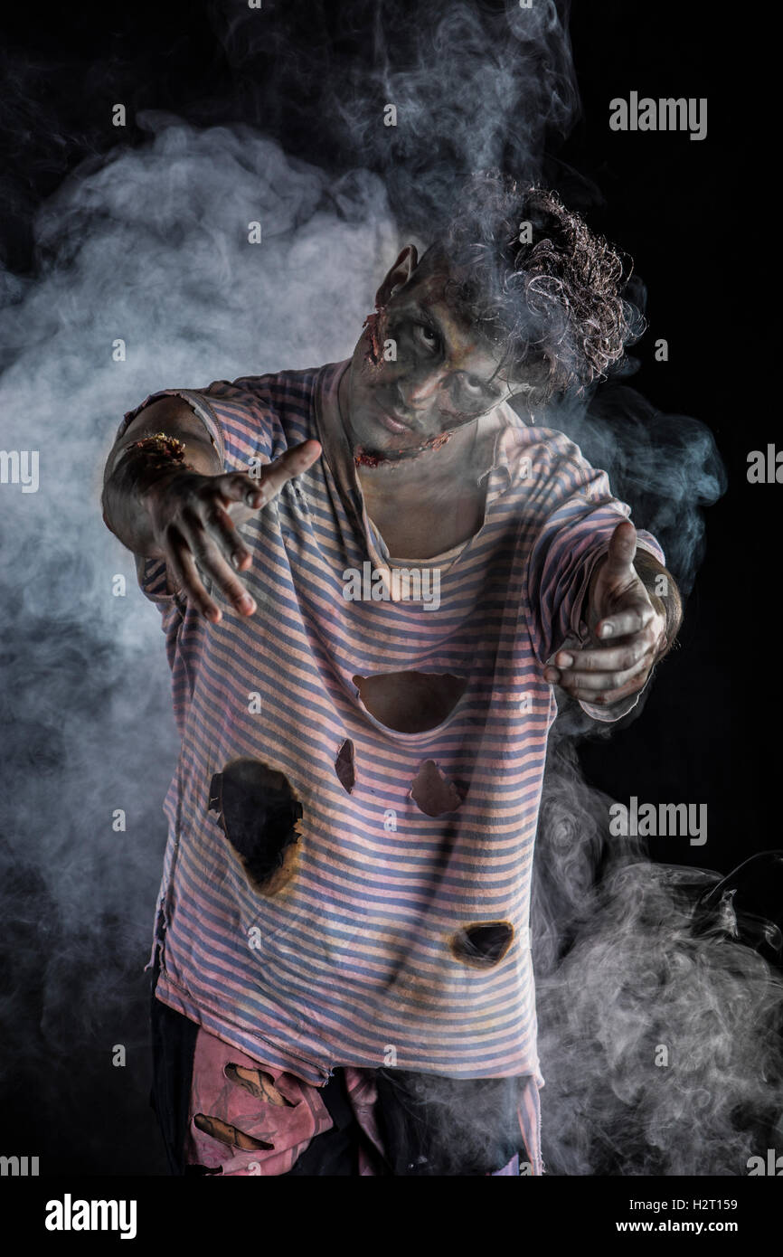 Male zombie standing on black smoky background, reaching hand towards ...
