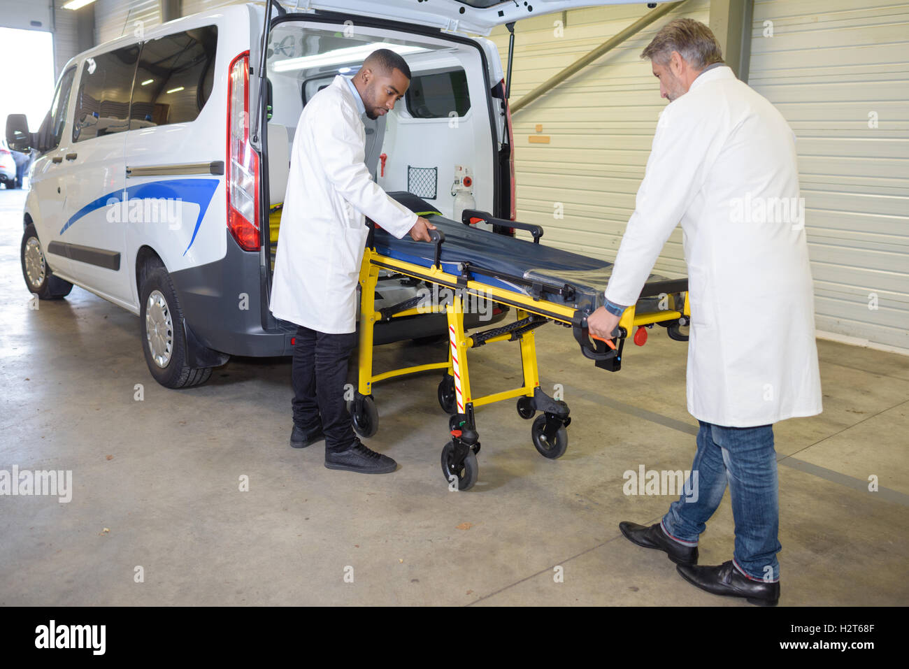 Paramedics loading stretcher into ambulance Stock Photo - Alamy