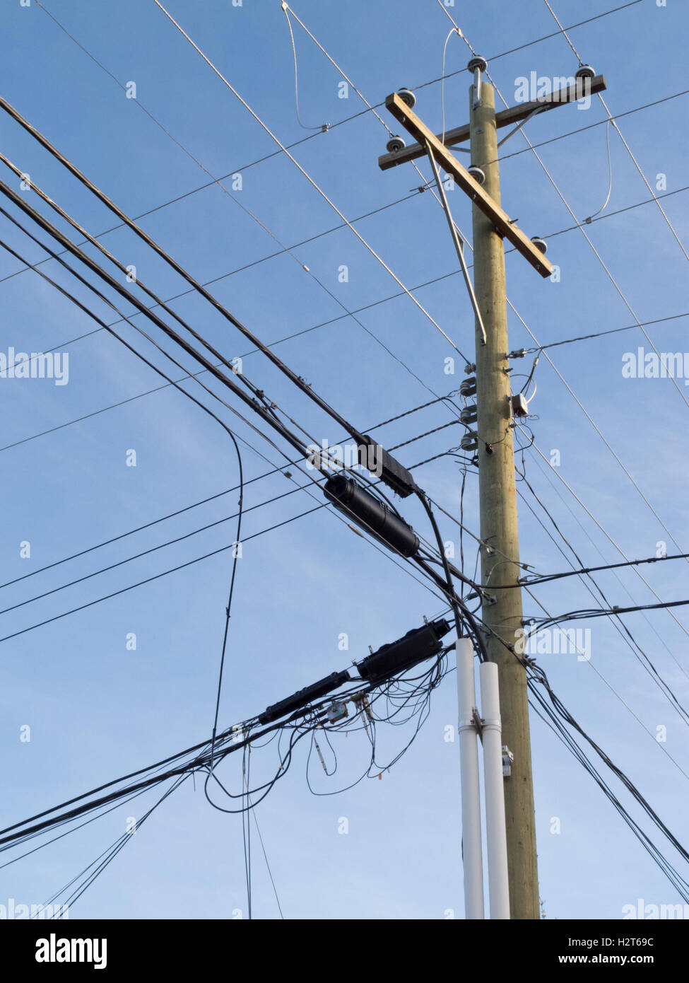 Wooden pole confusing power cable phone line mess Stock Photo - Alamy