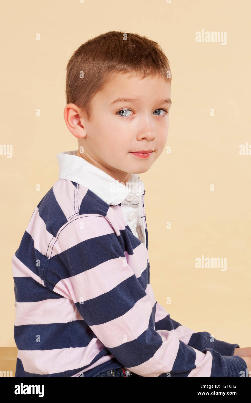 Young boy sitting and looking into camera isolated Stock Photo - Alamy