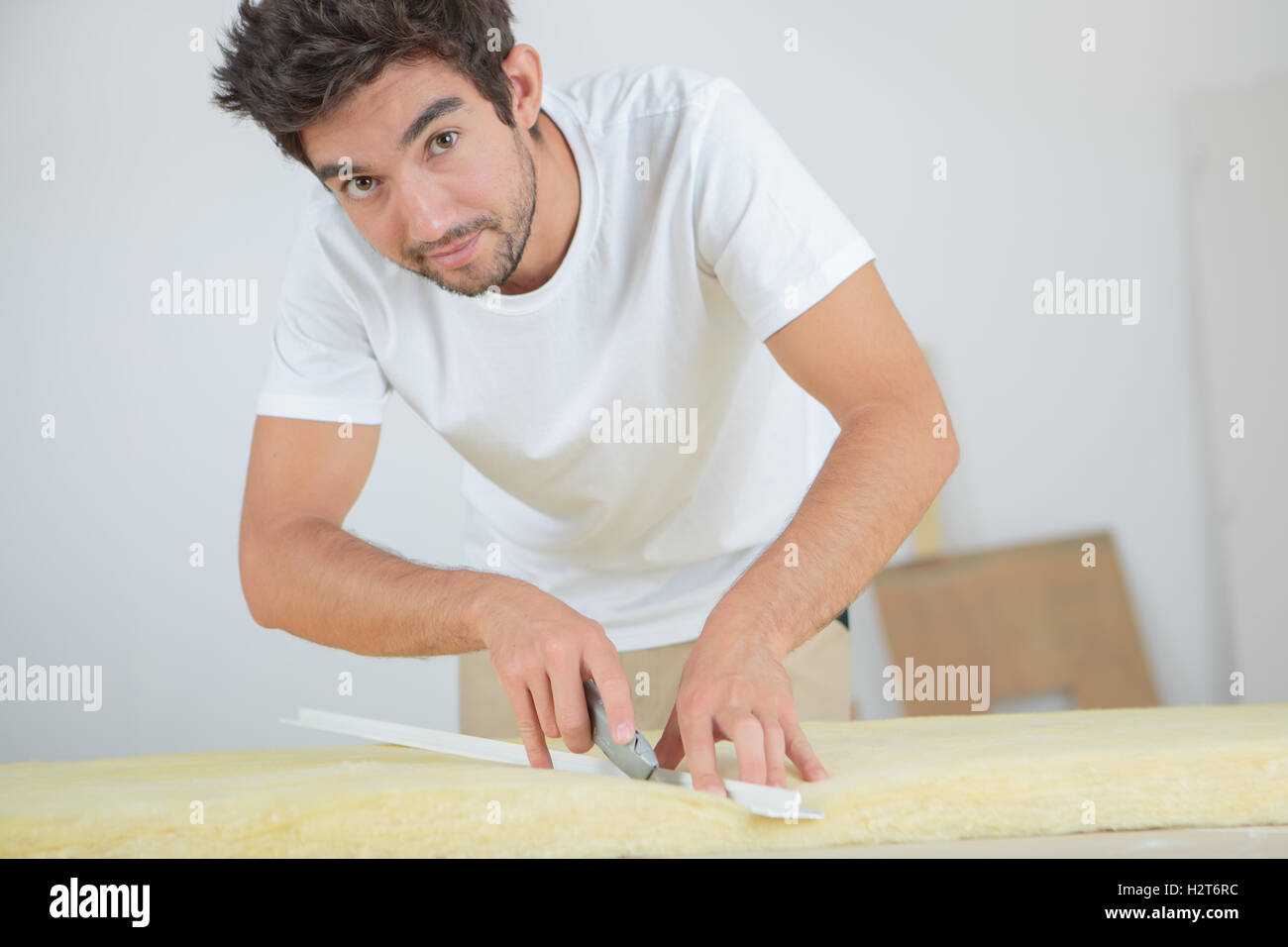 Tradesman cutting insulation Stock Photo - Alamy