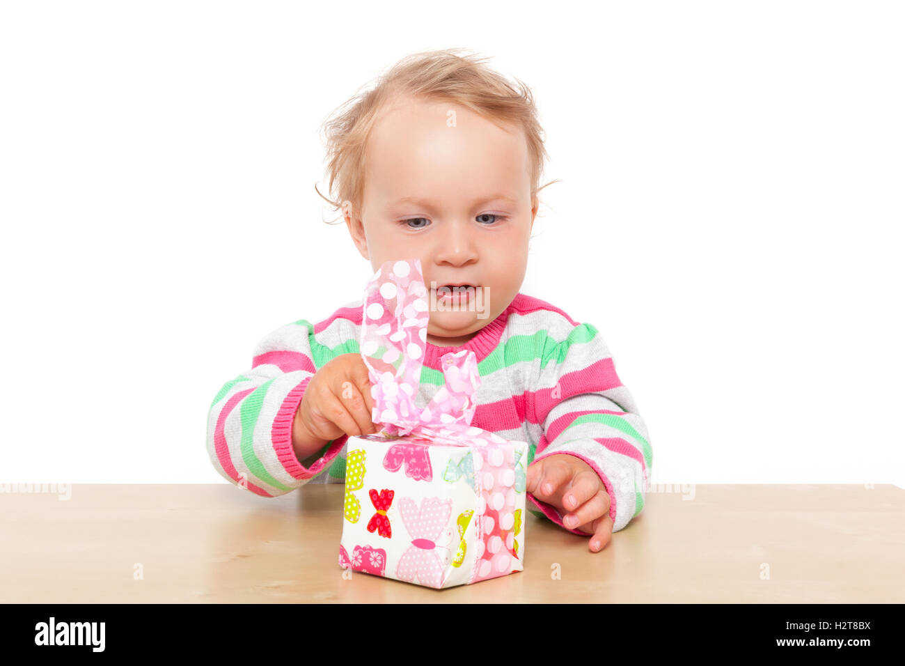 Baby girl unwrapping present Stock Photo - Alamy