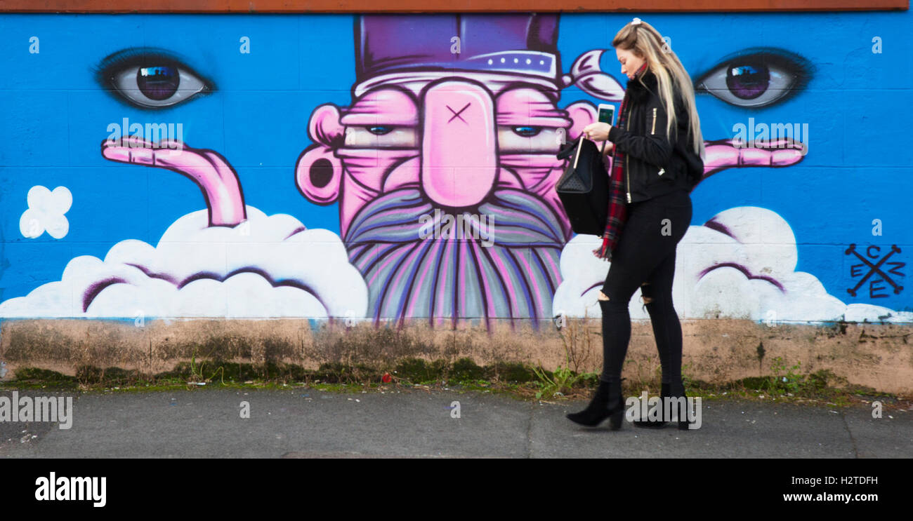 Pedestrian walking past street art, graffiti wall painting, decoration ...