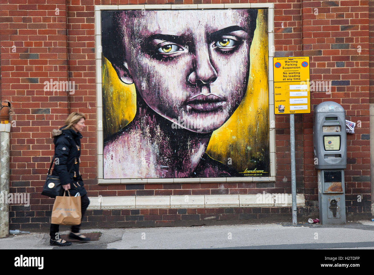 Sad portrait of ethnic woman. Pedestrian walking past street art ...