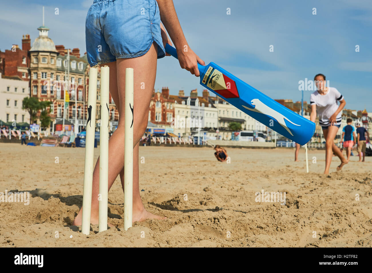 Family and friends enjoying a game of beach cricket on a sandy beach ...