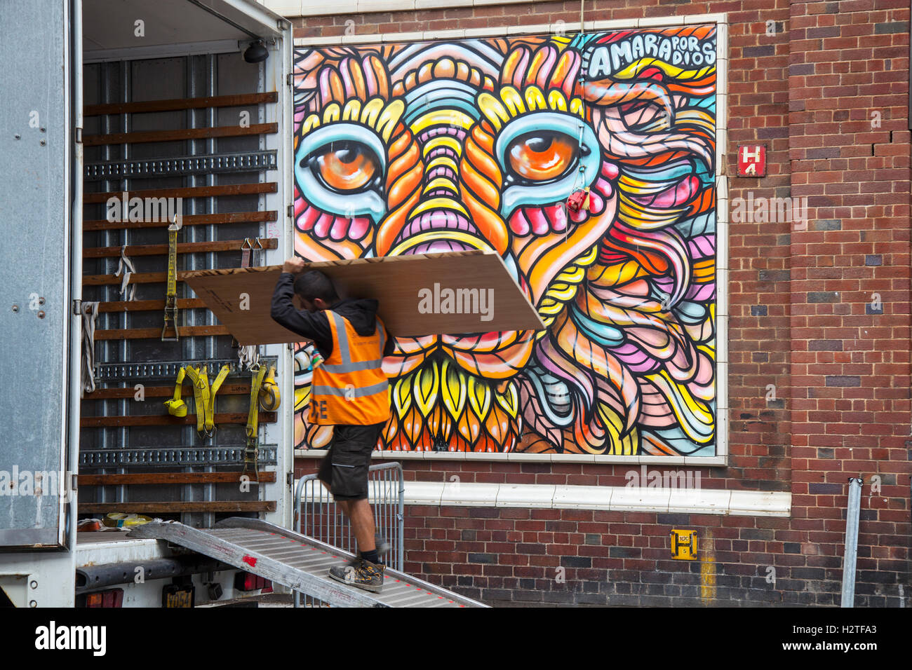 Pedestrian walking past street art, graffiti wall face painting ...