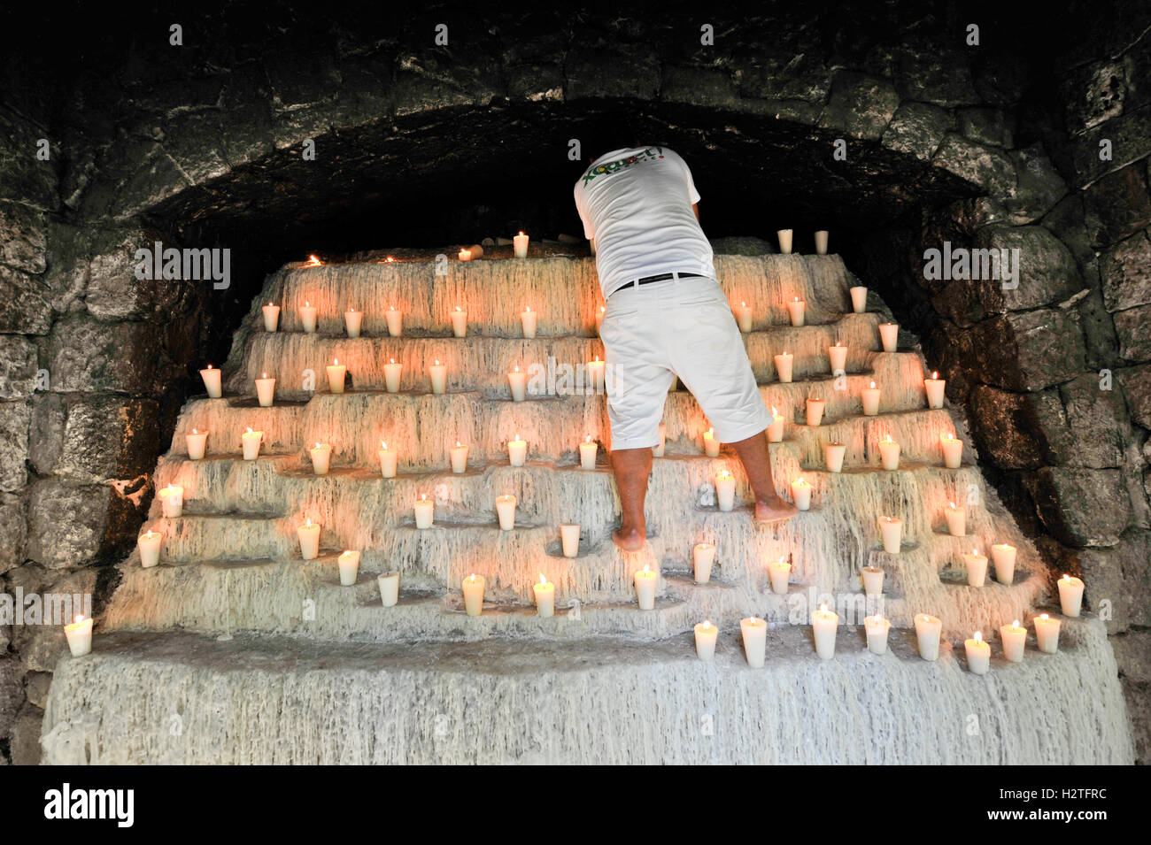 Xcaret park worker placing new candles in a grotto Stock Photo - Alamy