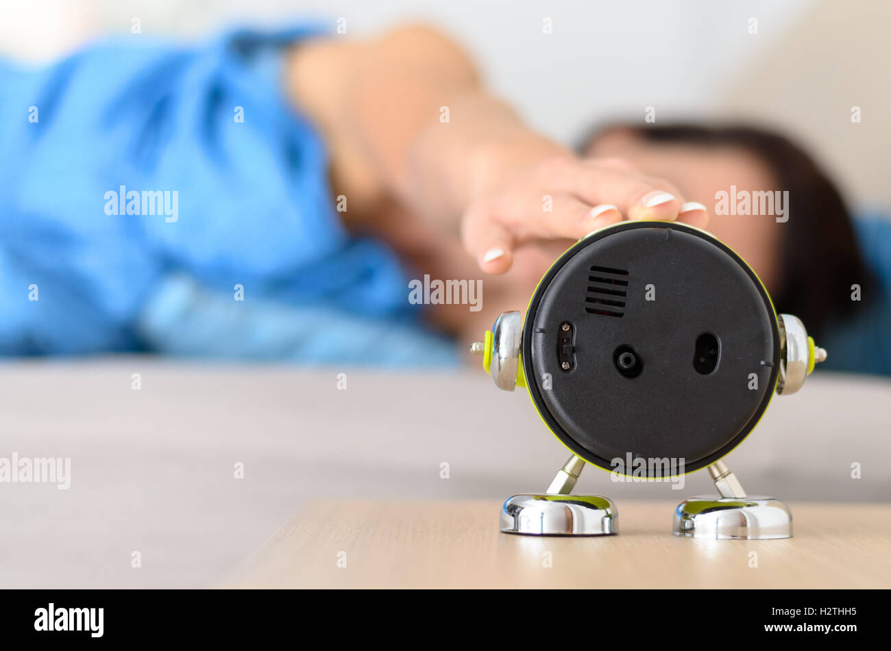 Woman stretching out to shut down the alarm clock as it wakens her in ...