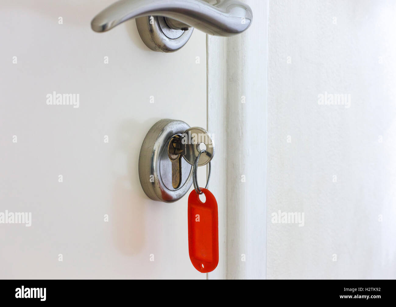 White door with key inside of keyhole Stock Photo - Alamy