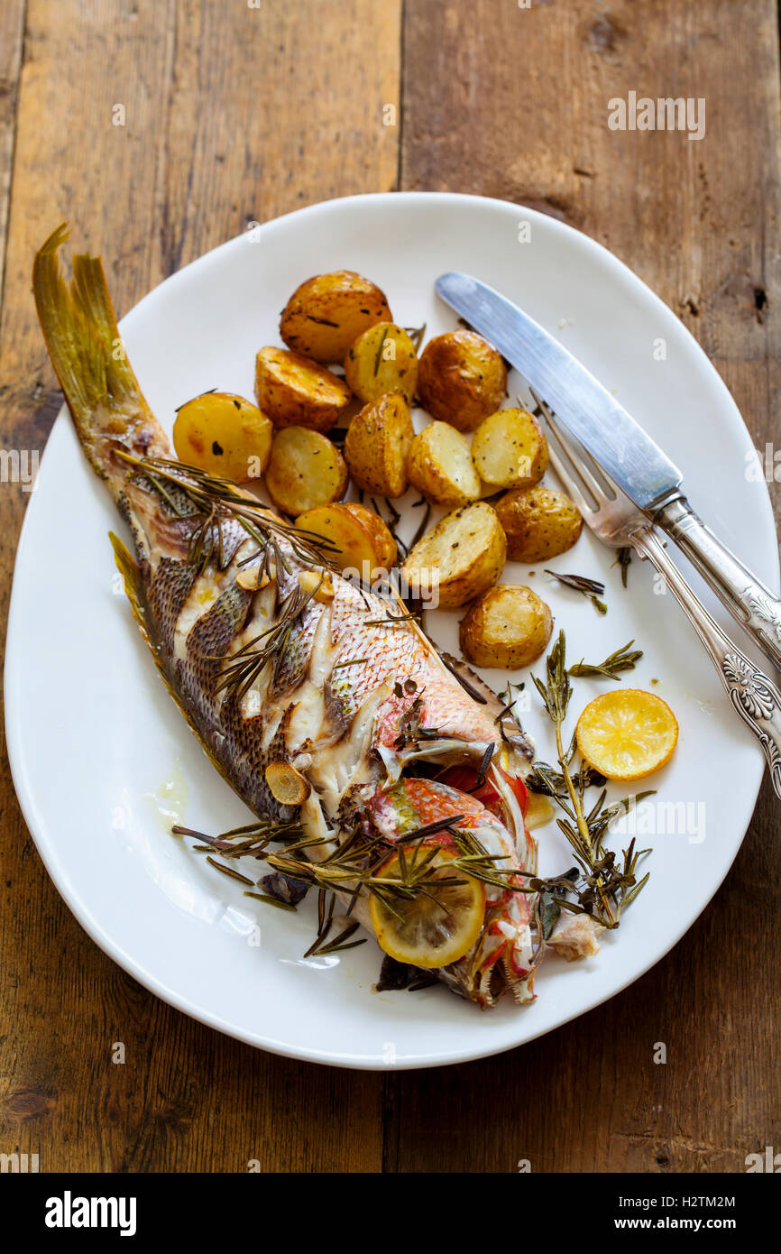 Roast red snapper with roast rosemary potatoes Stock Photo - Alamy