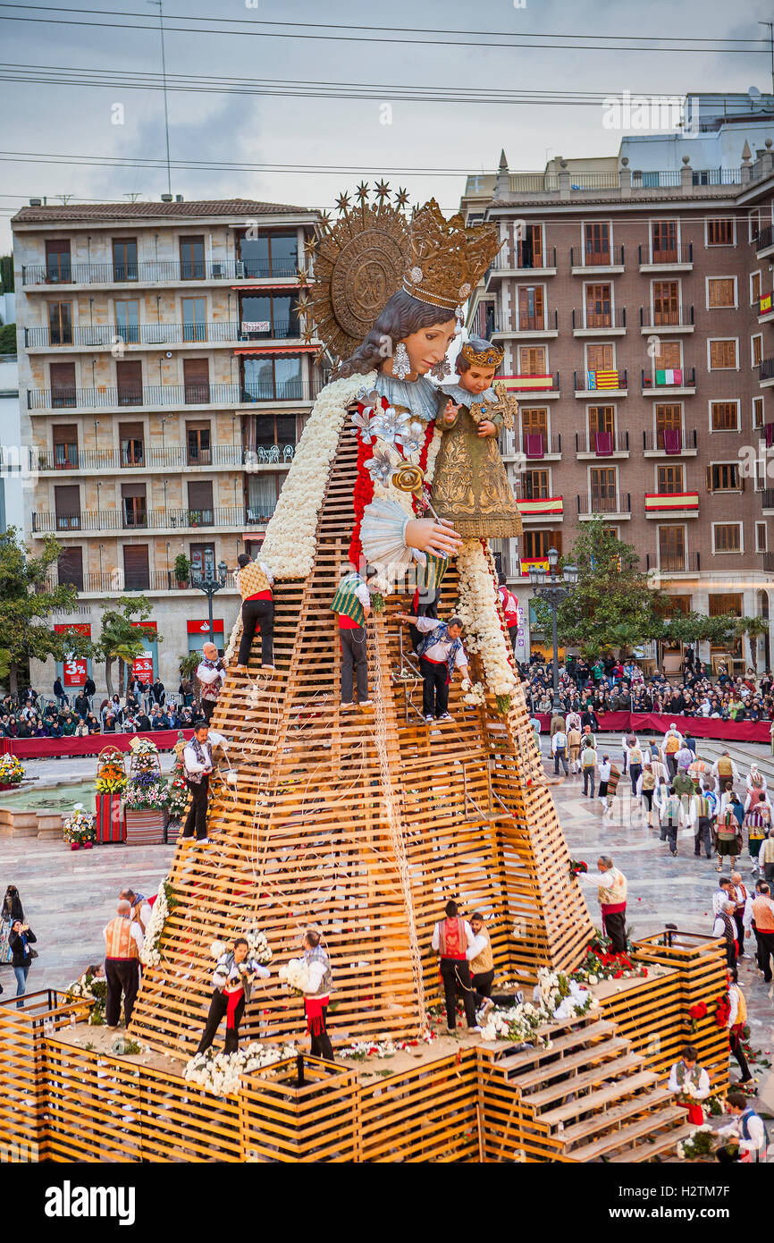 Men placing flower offerings on large wooden replica statue of Virgen ...