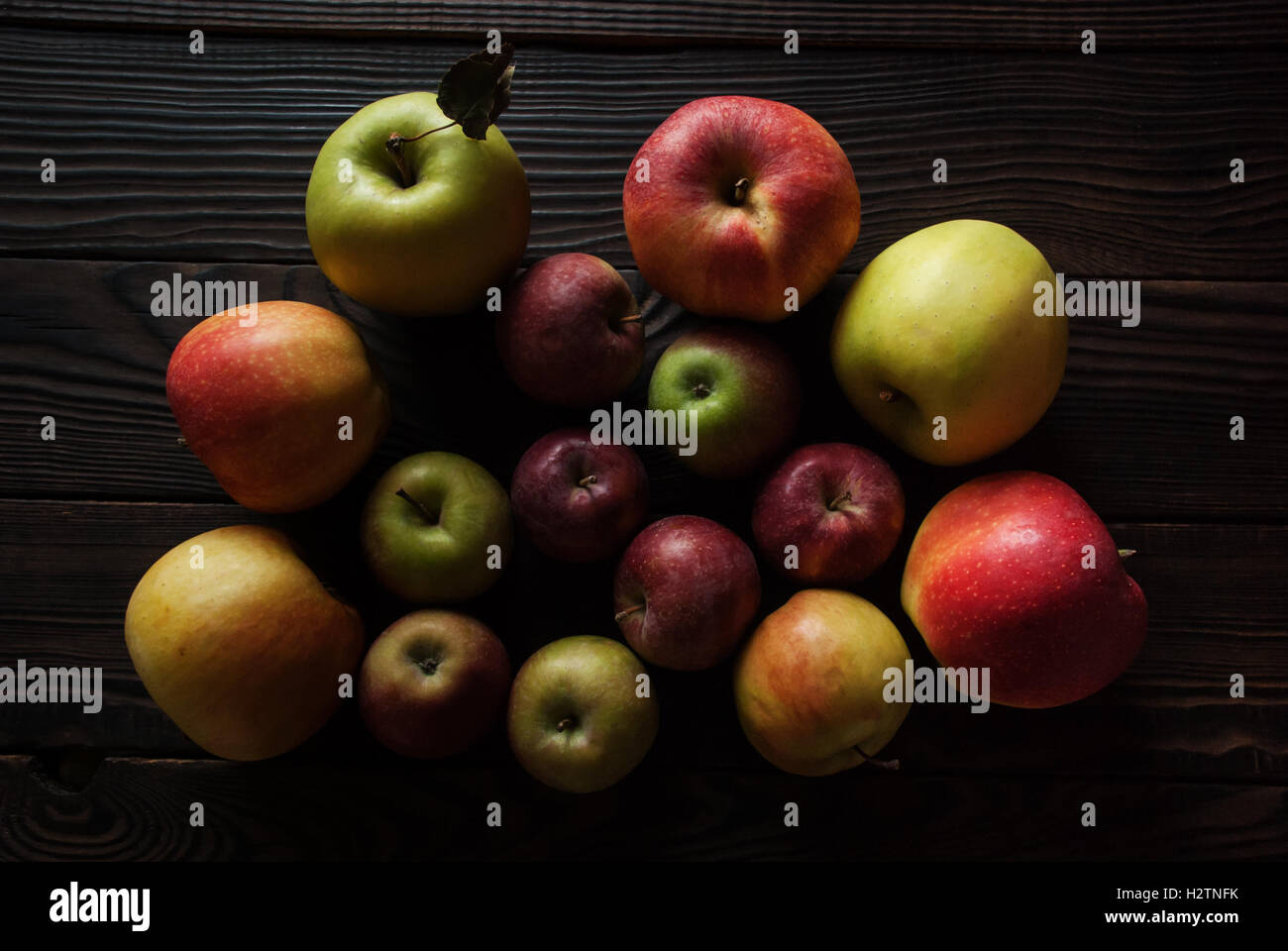 Group of colored apples of different sizes on a wooden surface Stock ...
