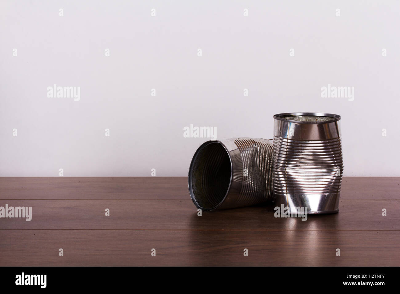 Battered tin cans on a rustic wooden background Stock Photo - Alamy