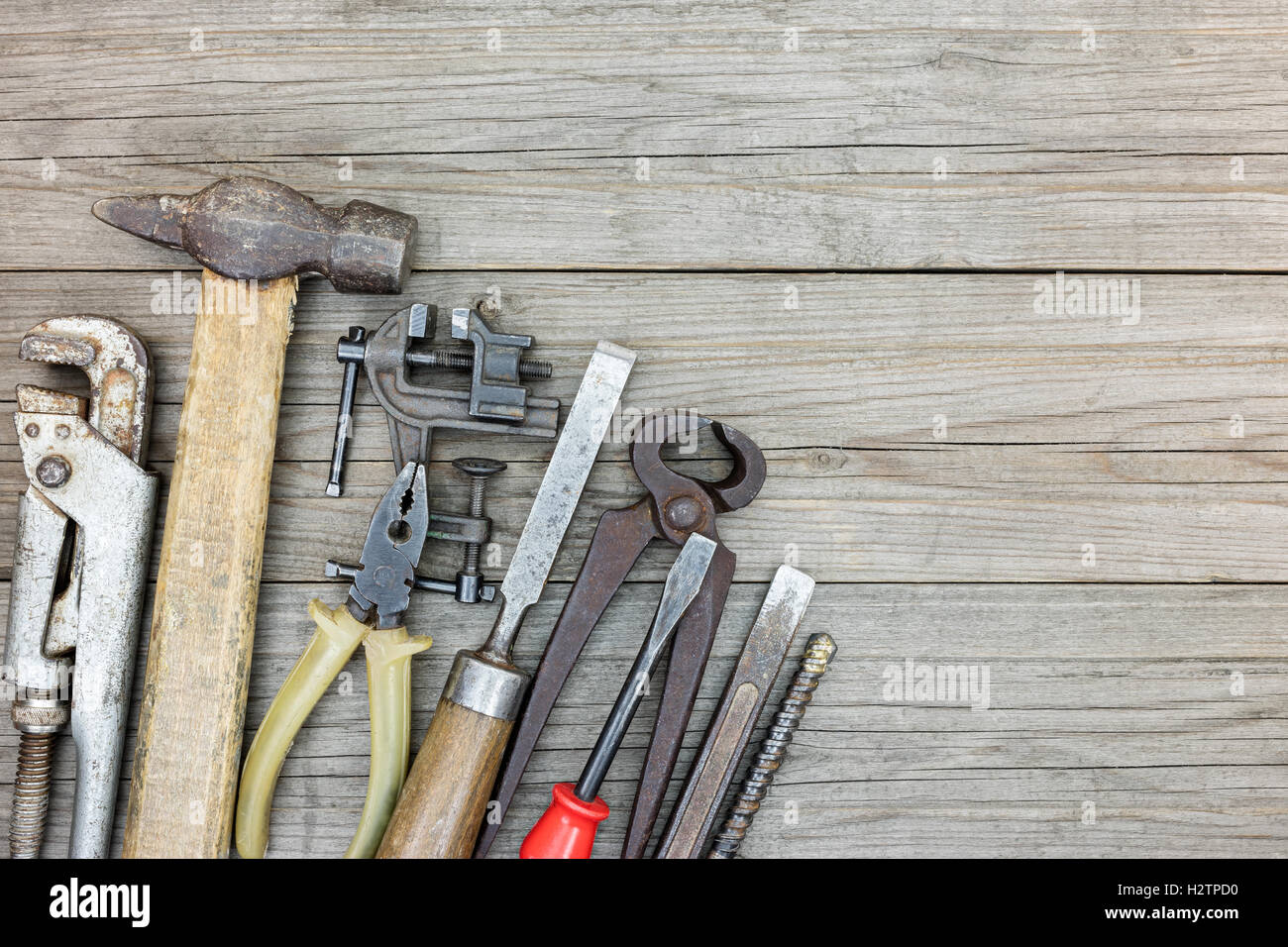 set of old rusty hand tools for repair and fixing on grey wooden plank ...