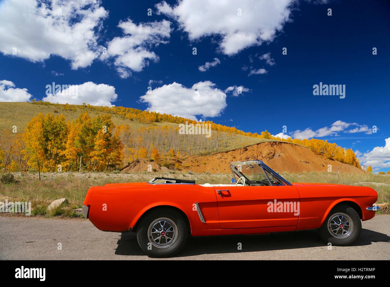 Classic orange colored convertible sports car on mountain road with ...