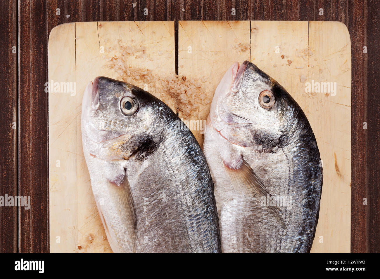 Two fish on wooden cutting board Stock Photo - Alamy