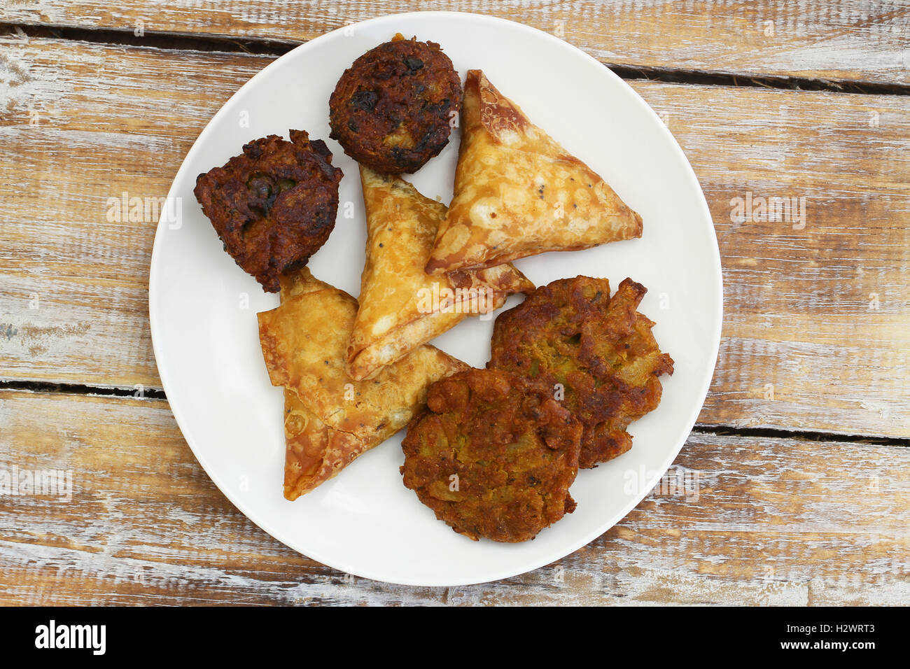 Indian snacks on white plate on rustic wooden surface Stock Photo - Alamy