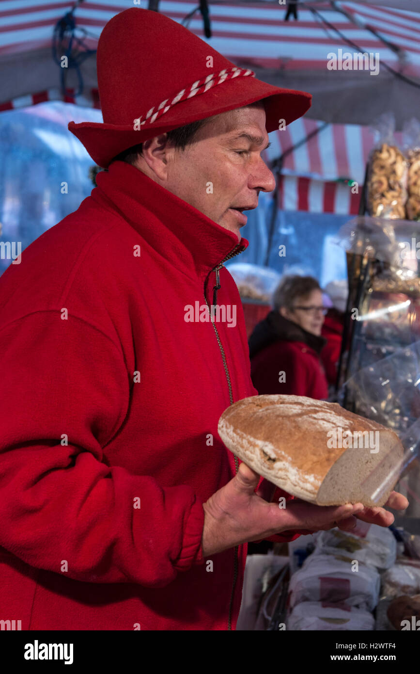 A baker wearing a Bavarian hat serving a customer at his stall during ...