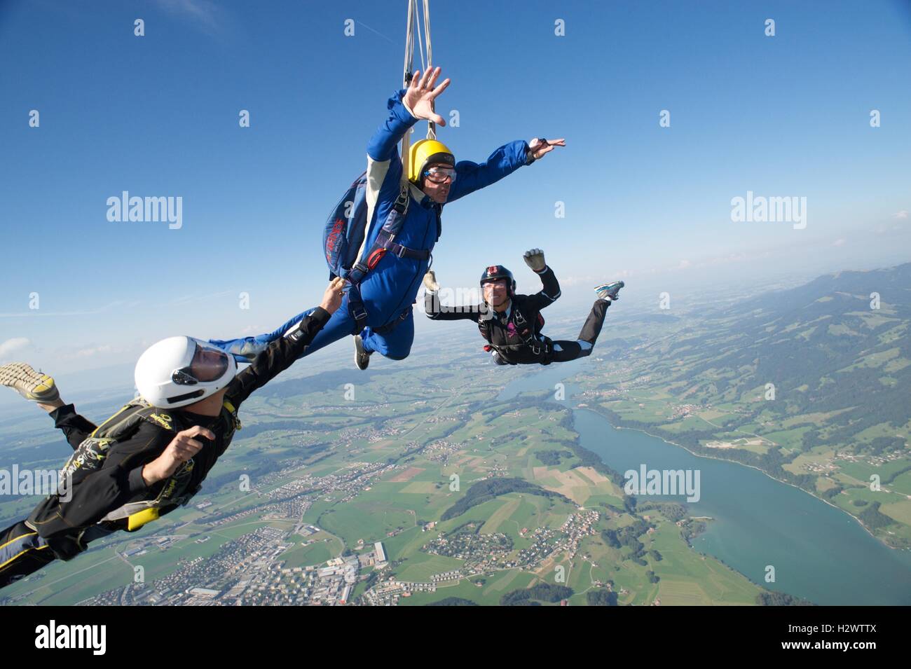Two instructors assist a student skydiver during the opening of his ...