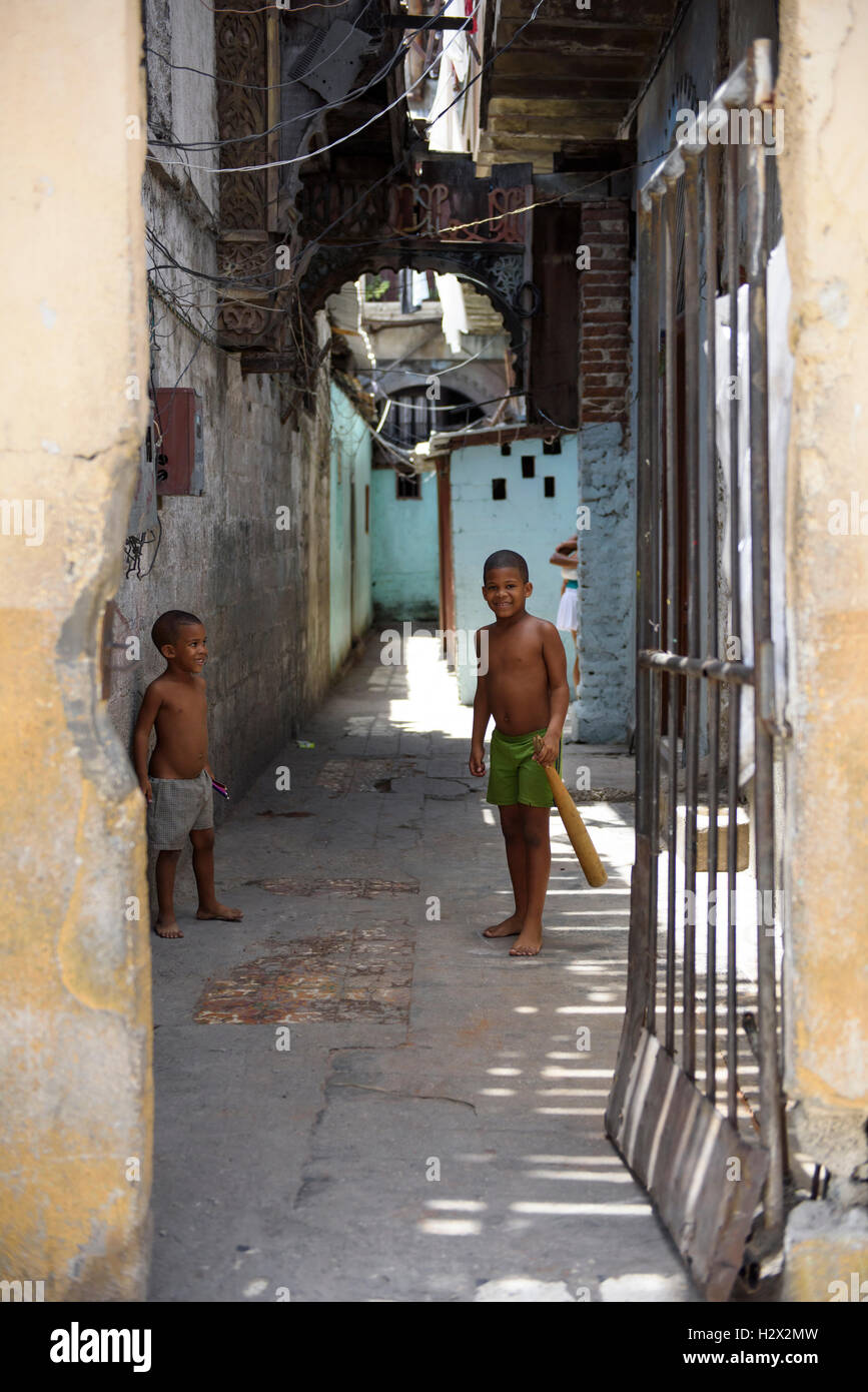 Two little barefoot boys smiling from behind the open gate of their ...