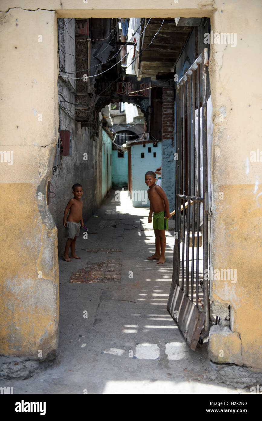 Two little barefoot boys smiling from behind the open gate of their ...