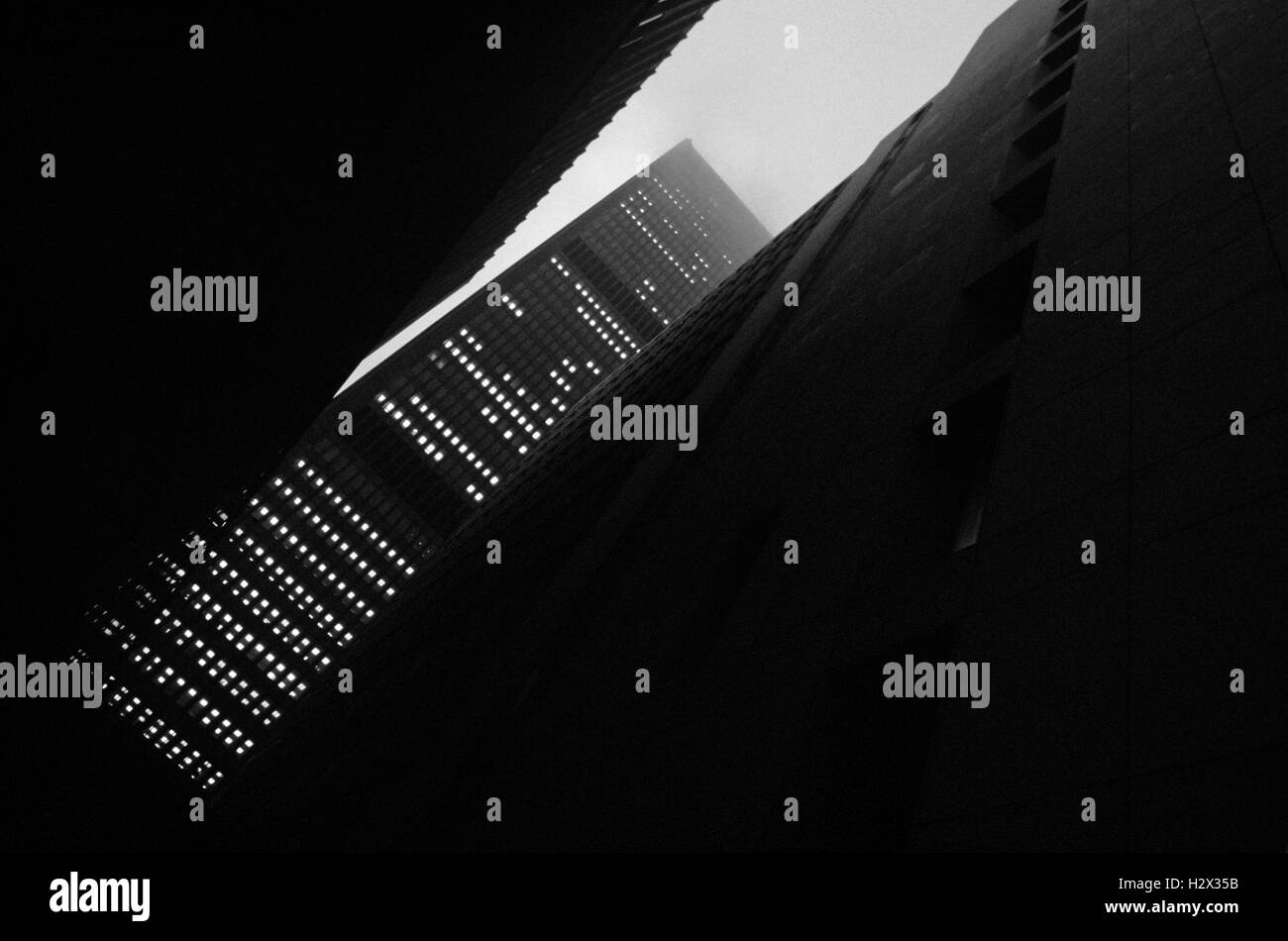 Downtown Skyscraper leaning between buildings sunrise in fog looking up ...