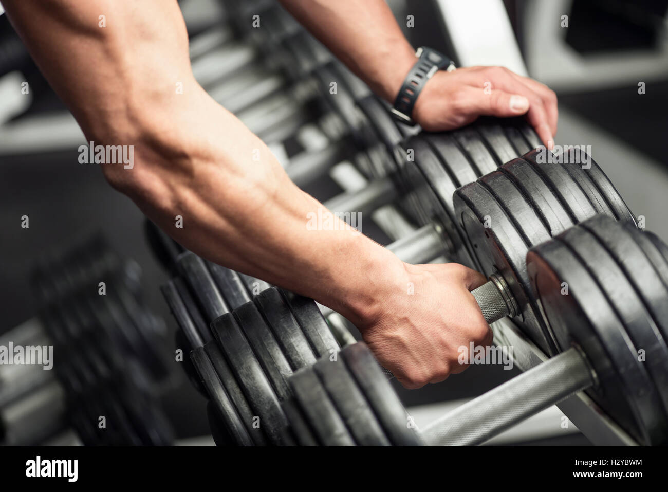 Strong well built bodybuilder lifting a dumbbell Stock Photo - Alamy