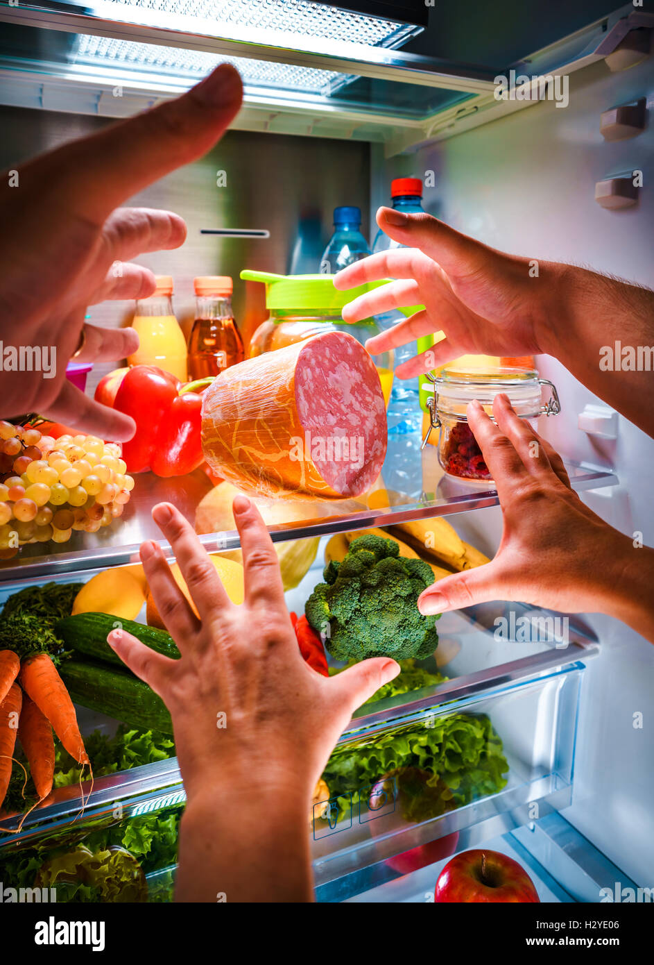 Human hands reaching for food at night in the open refrigerator Stock ...