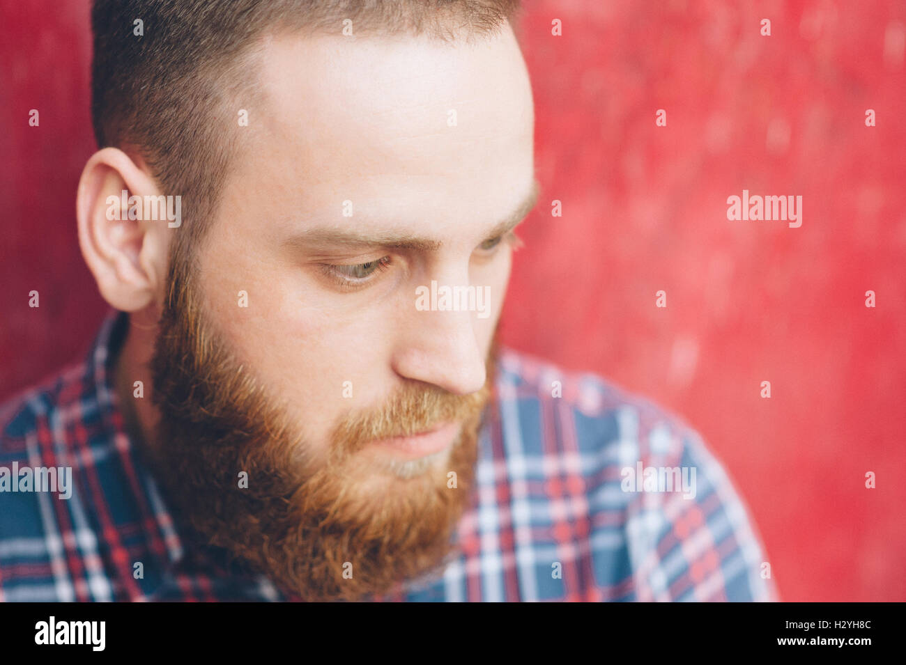 brooding, bearded young man on a background of red wall Stock Photo - Alamy