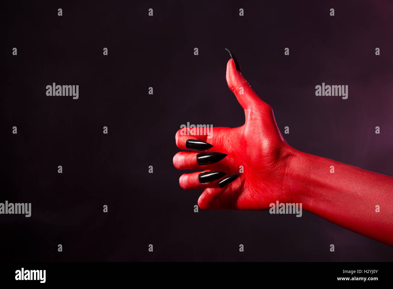 Spooky red devil hand showing thumbs up Stock Photo - Alamy