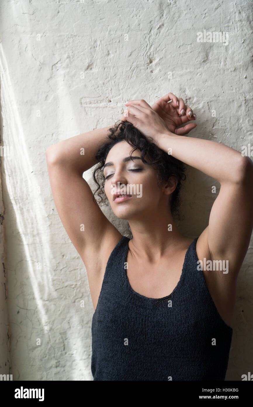 Beautiful woman standing against the wall hands over head Stock Photo ...