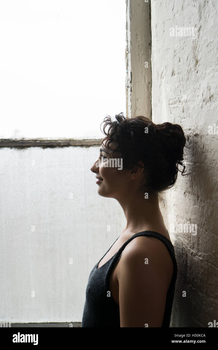 Happy young woman looking out the window smiling Stock Photo - Alamy