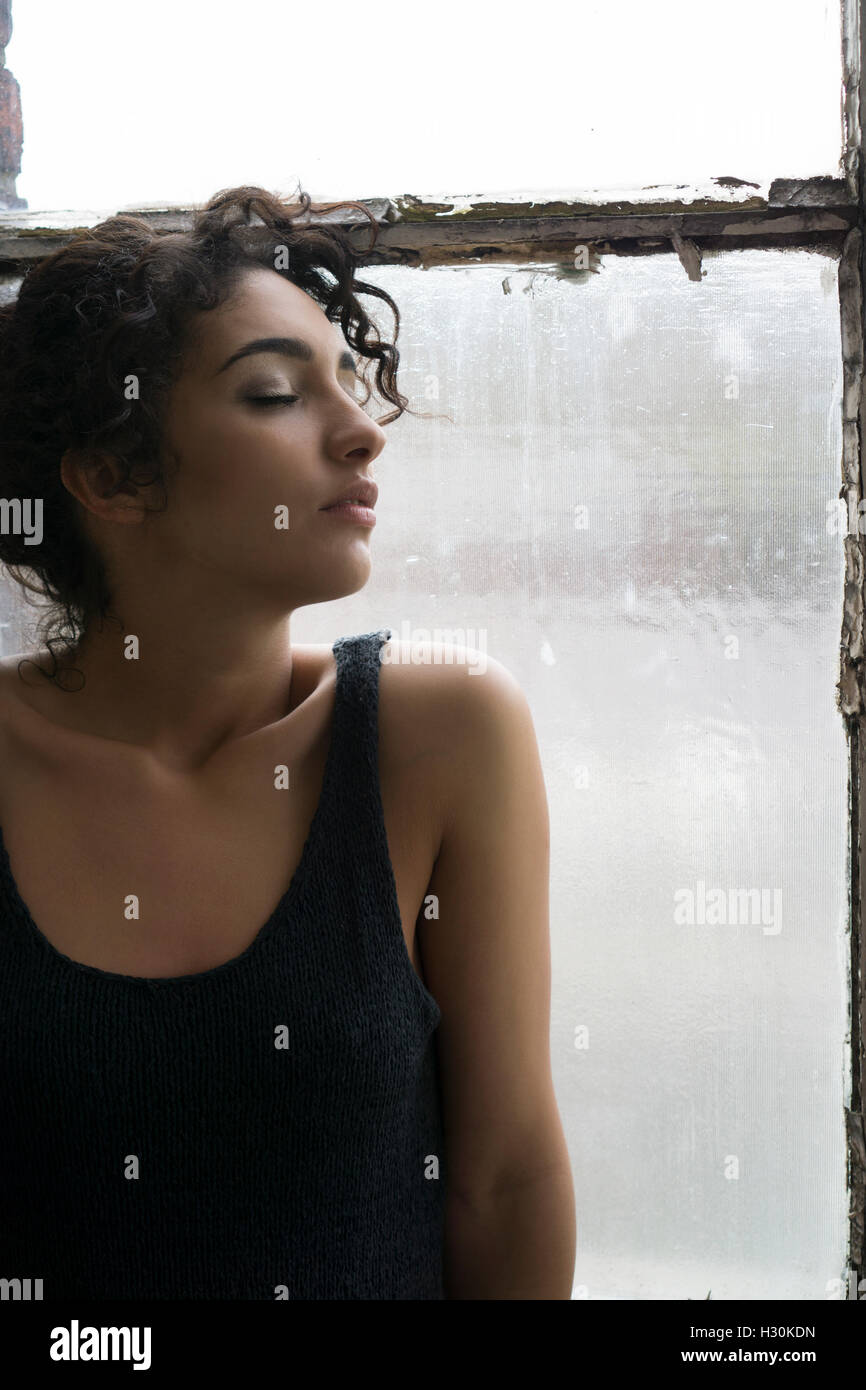 Beautiful young woman standing by the window Stock Photo - Alamy