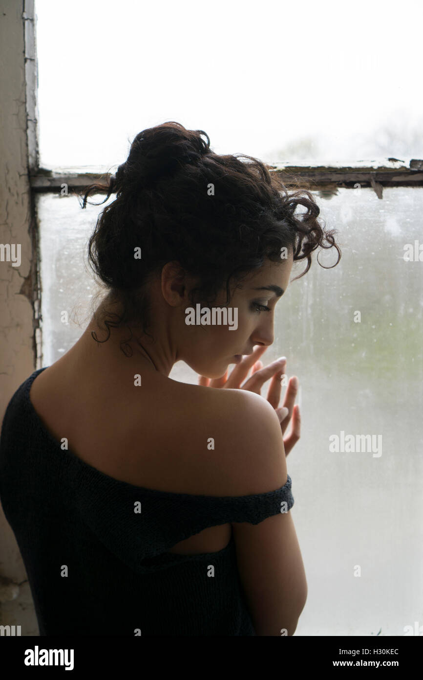Beautiful young woman standing by the window Stock Photo - Alamy