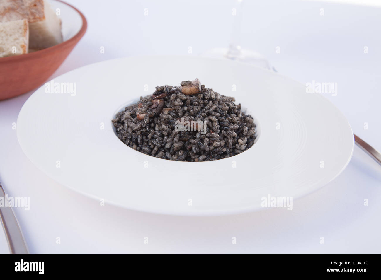 top aerial view of white circular plate with black ink squid rice dish ...