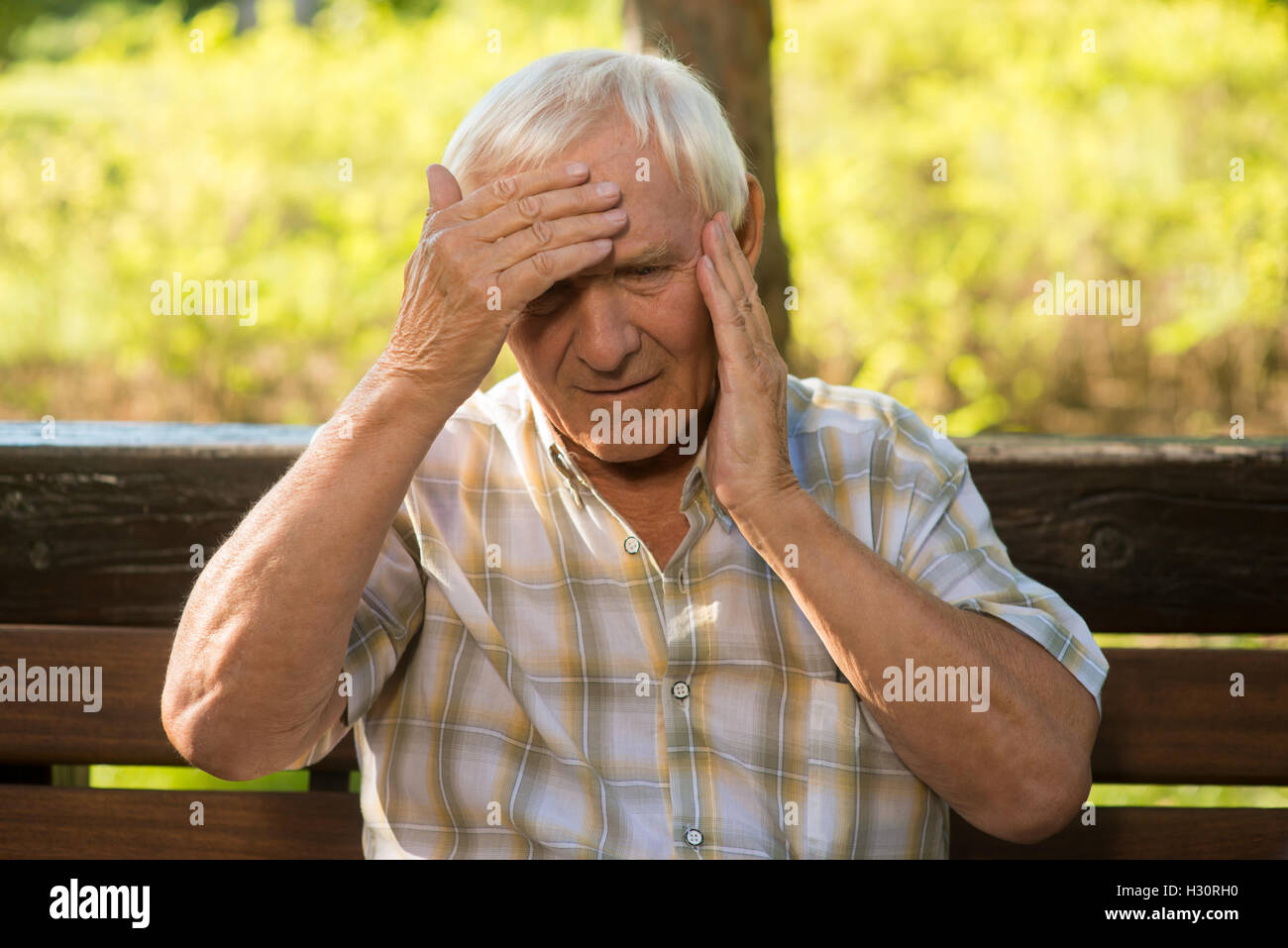 Senior man holding his head Stock Photo - Alamy
