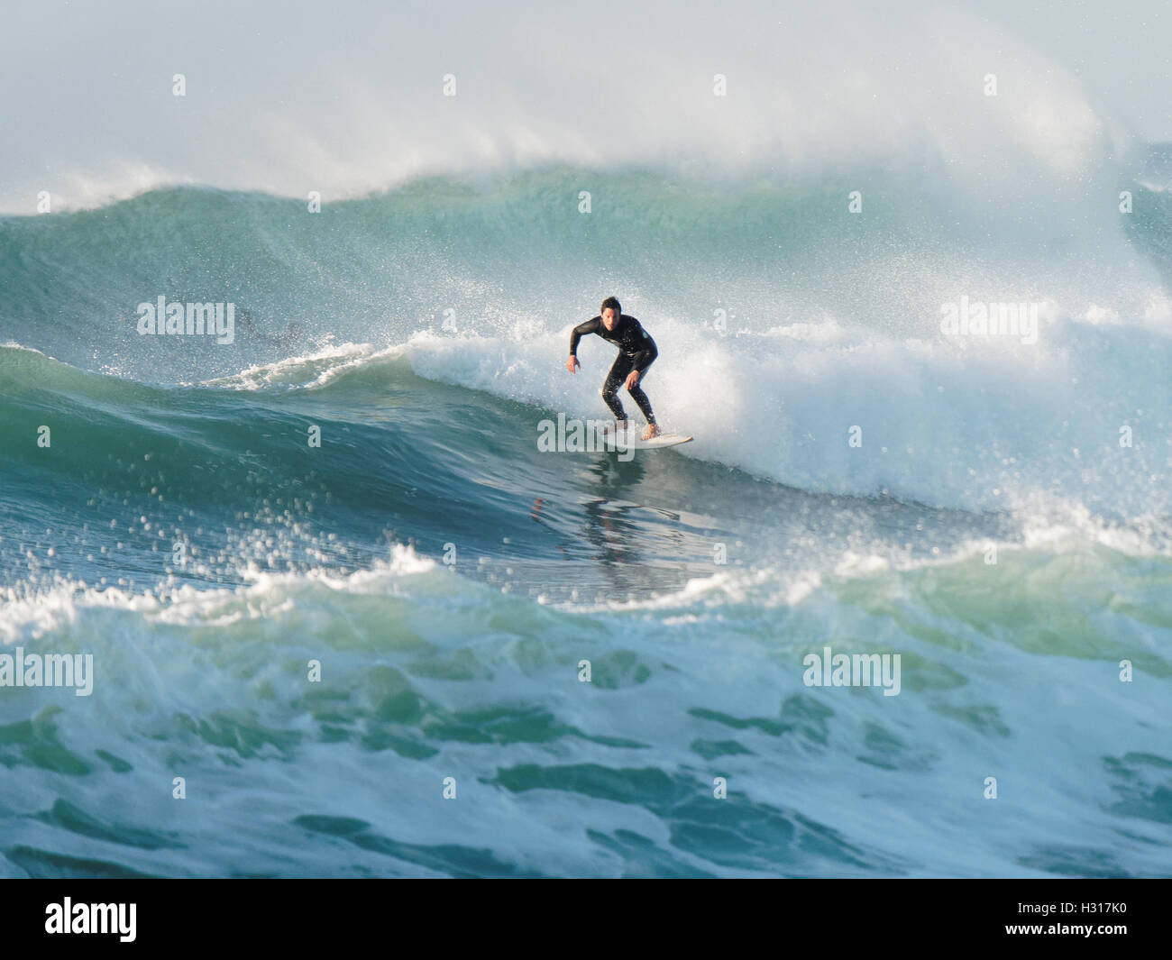 Lone surfer rides huge back lit sunshine surf UK Stock Photo - Alamy