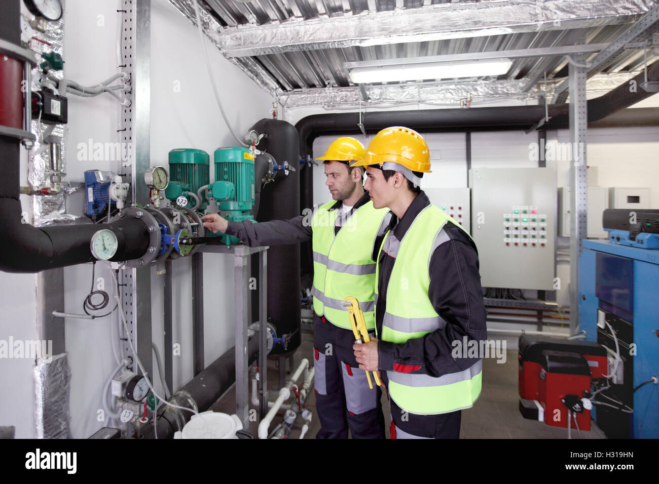Two workers in hardhats at plant checking parameters of pressure Stock ...