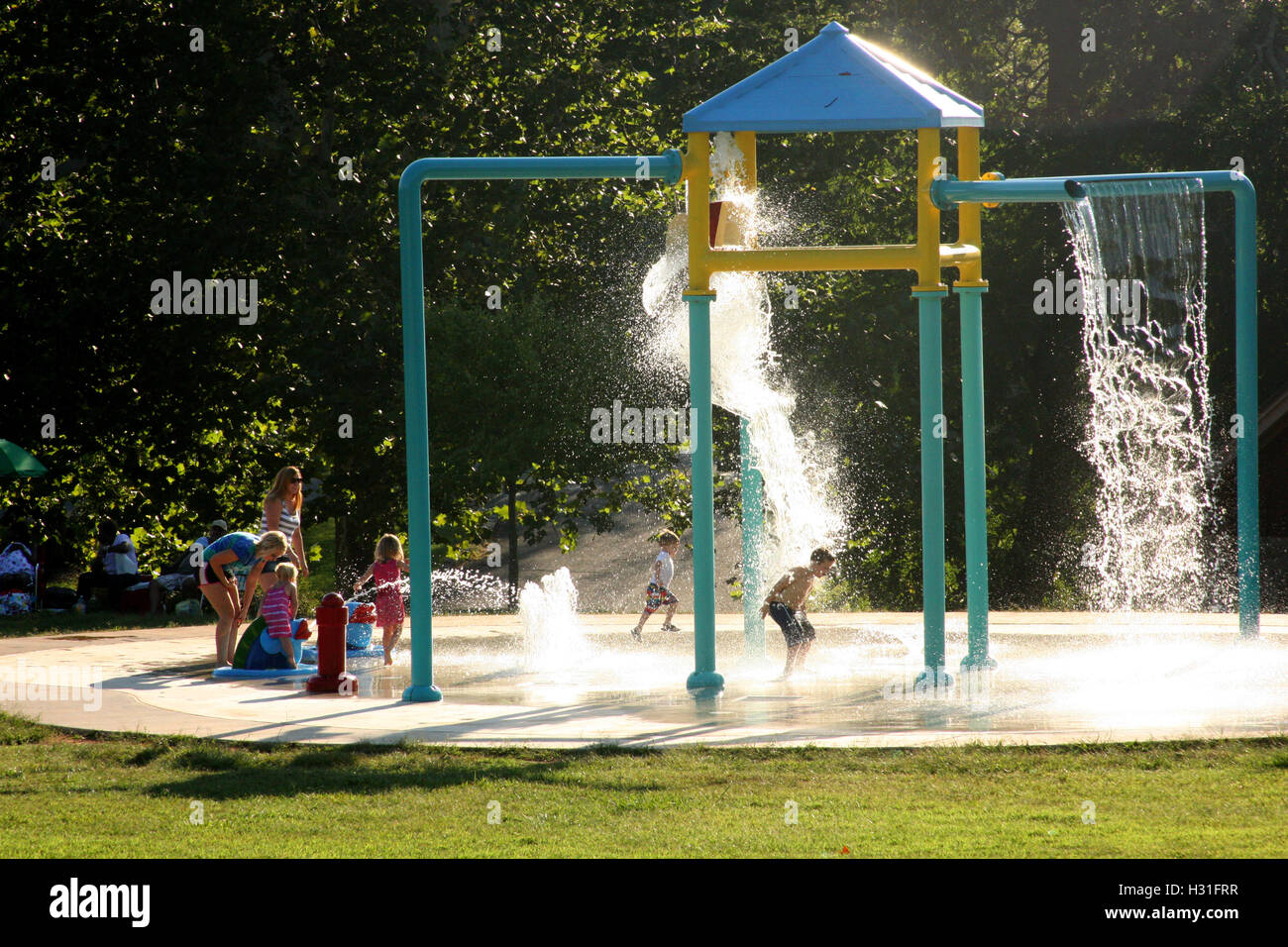 Children playing at sprayground in a summer day Stock Photo - Alamy