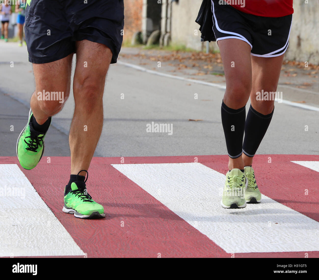 two runners during a marathon race in the city on a pedestrian crossing ...