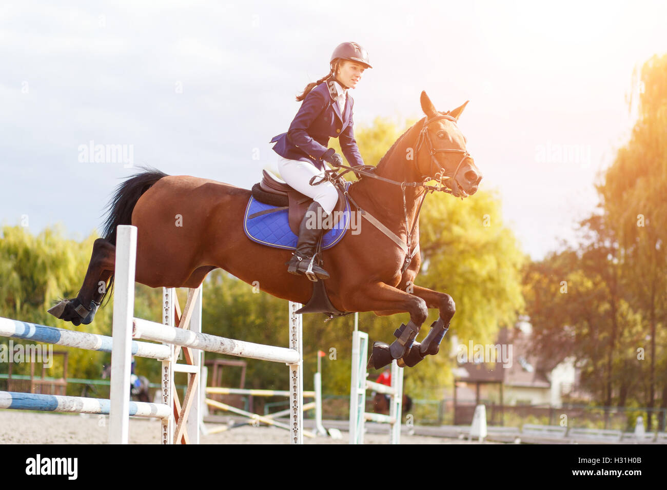 Young rider girl performing jump at horse show jumping competition. Equestrian sport background ...