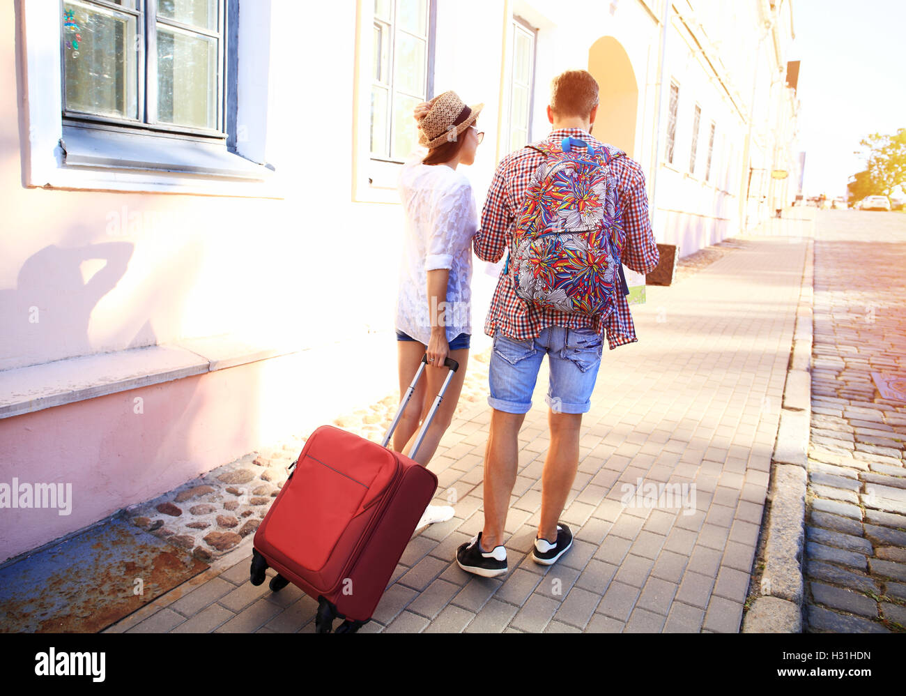 Two travelers on vacation walking around city with luggage Stock Photo ...