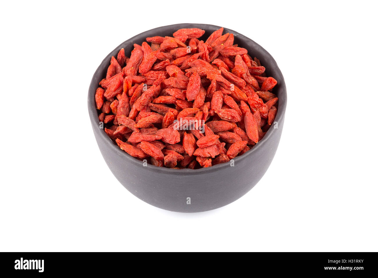 Chinese goji berries in dark stone bowl close up on white background ...