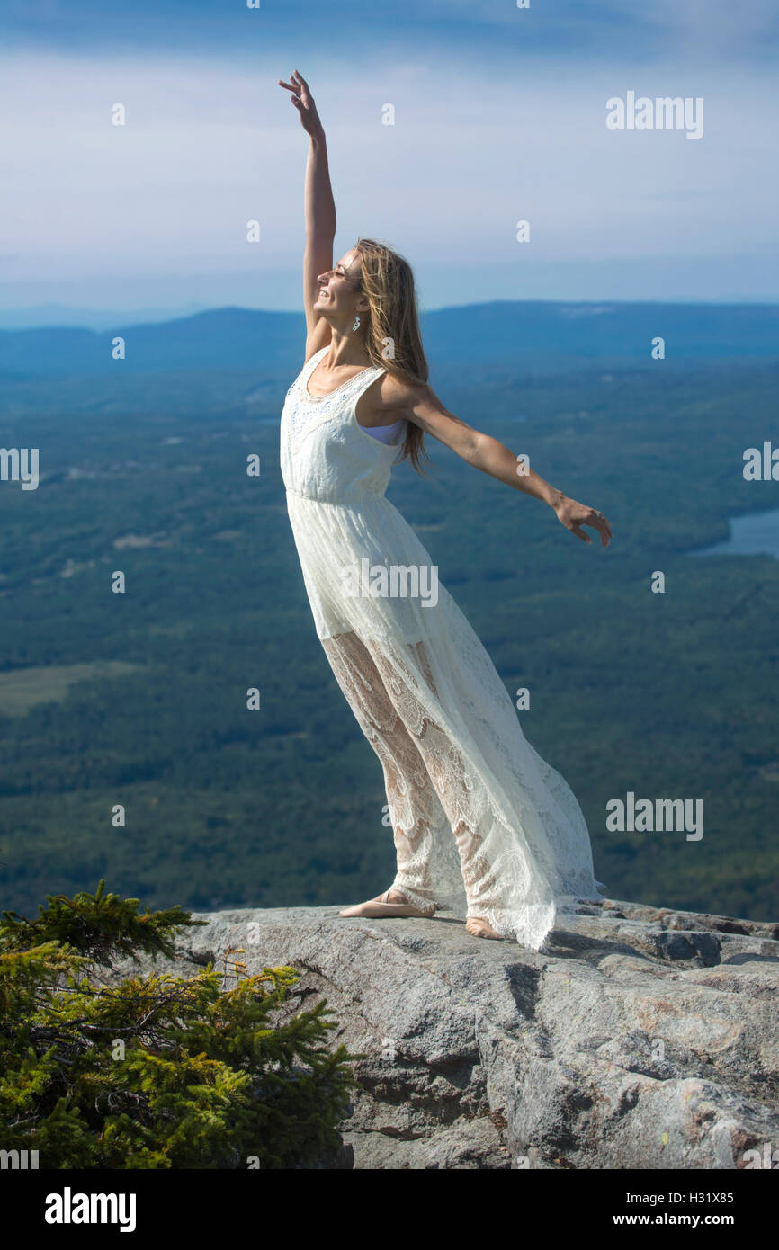 Female dancer in white dress dancing in the wind on summit of Mt ...
