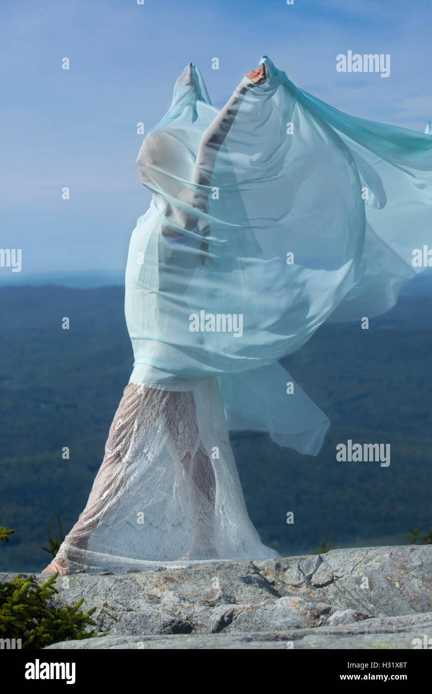 Female dancer in white dress wrapped inside green fabric blowing in the ...