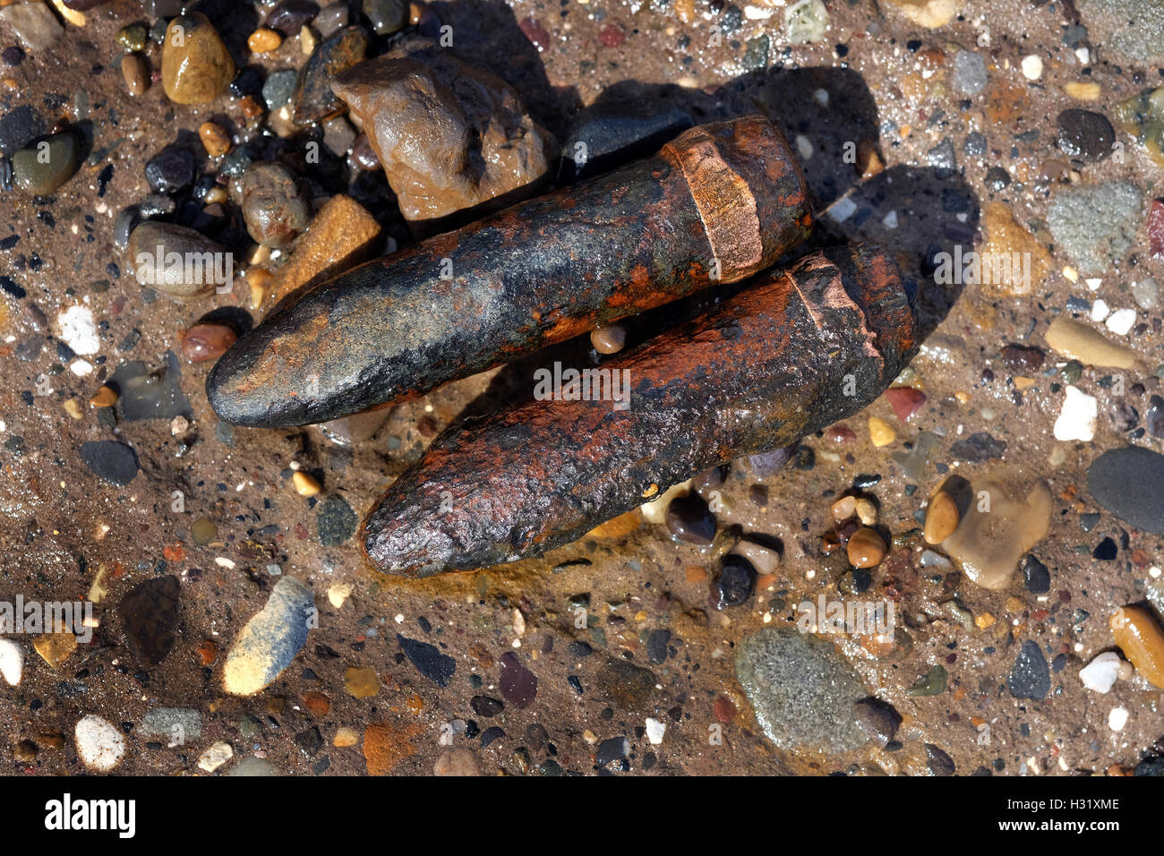 Spent world war two twenty millimeter cannon shells in wet sand on a ...
