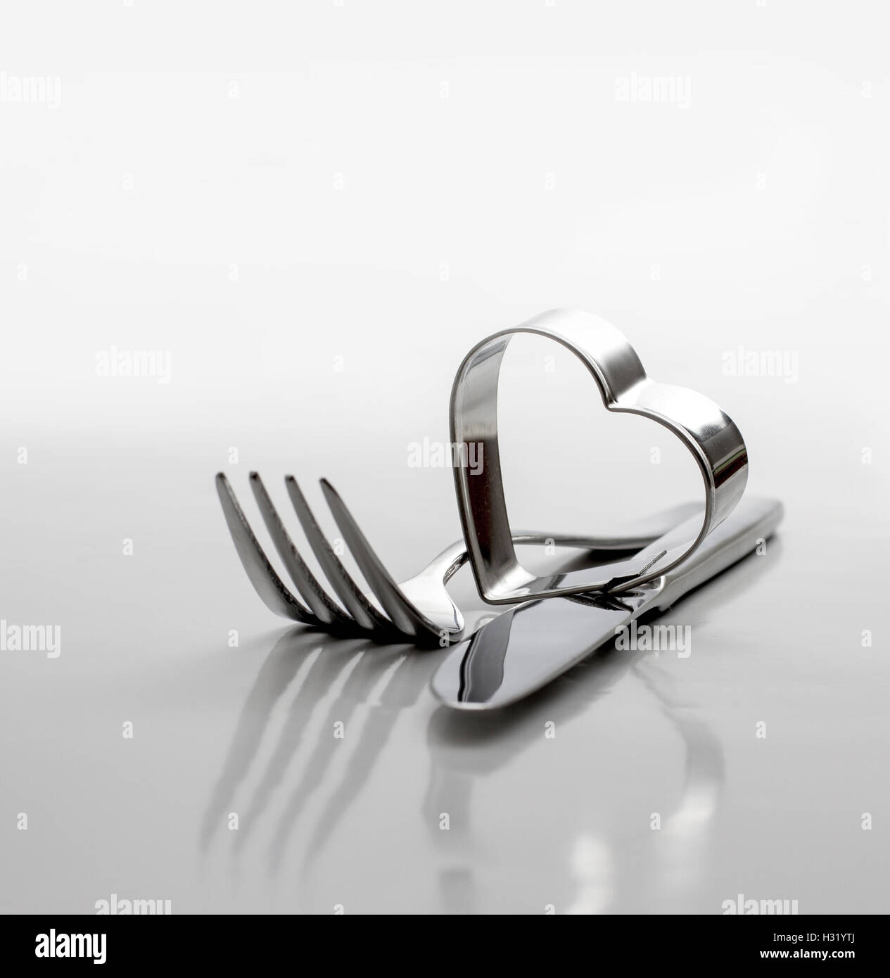 Cutlery, fork with knife and heart on grey background Stock Photo - Alamy